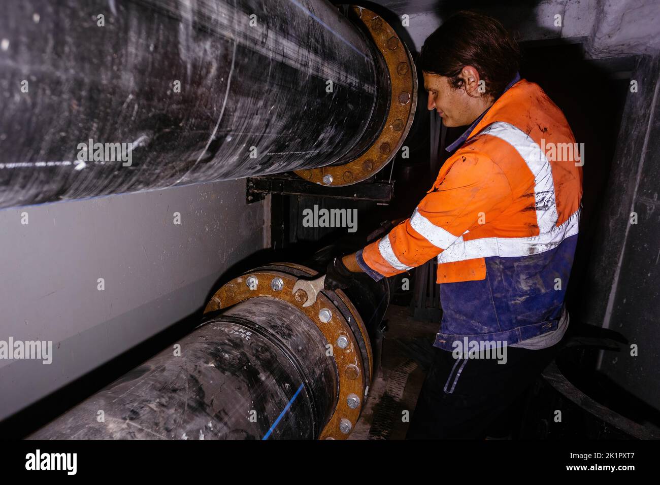 Worker installing water pipeline system in technical tunnel Stock Photo ...