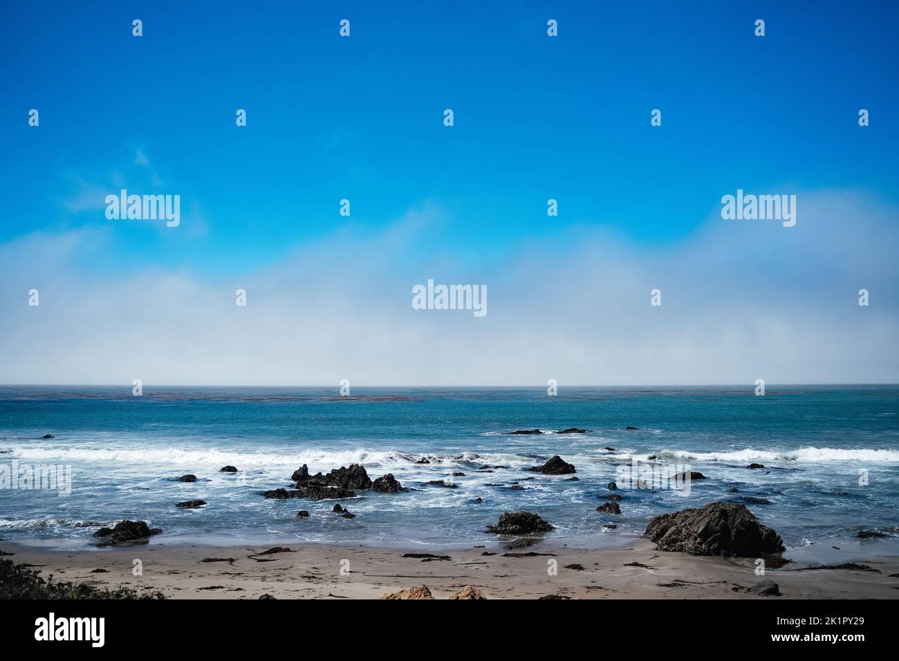 Pacific ocean beach with black rocks morning mist and blue sky. San ...