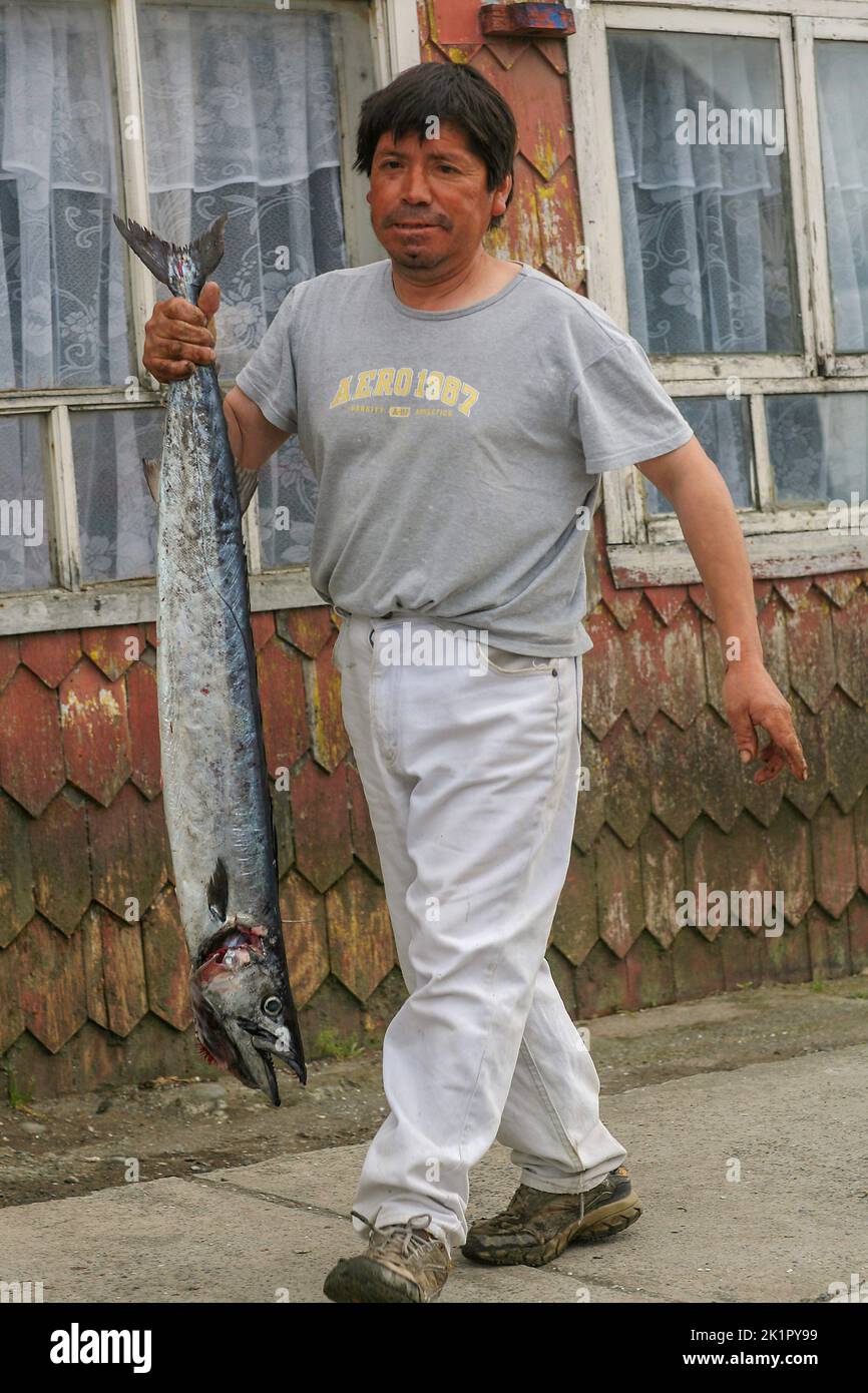 Chile, Chiloe island -man has bought a fish and brings it home. He ...