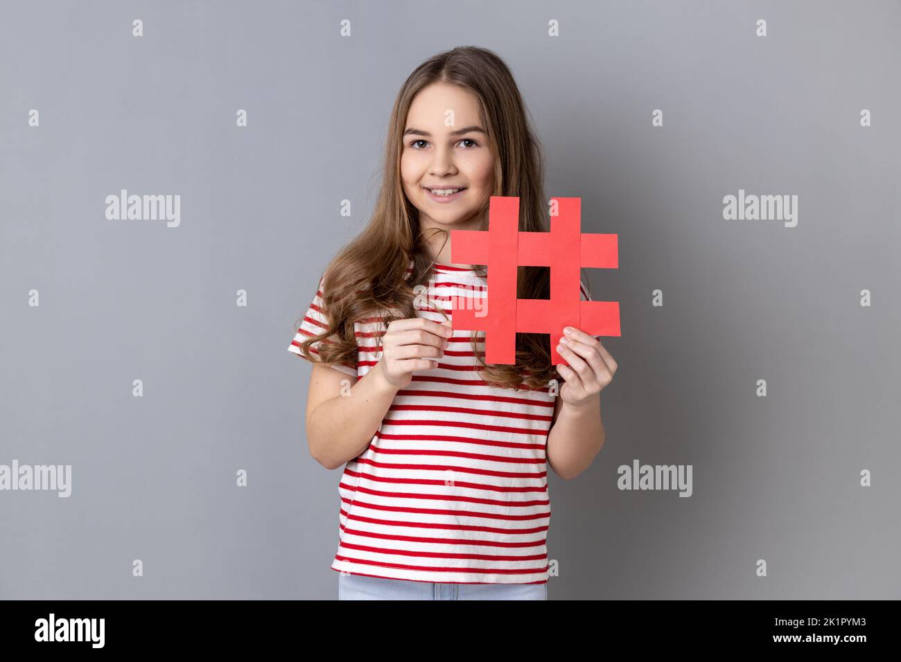 Portrait of delighted positive dark haired little girl wearing striped ...