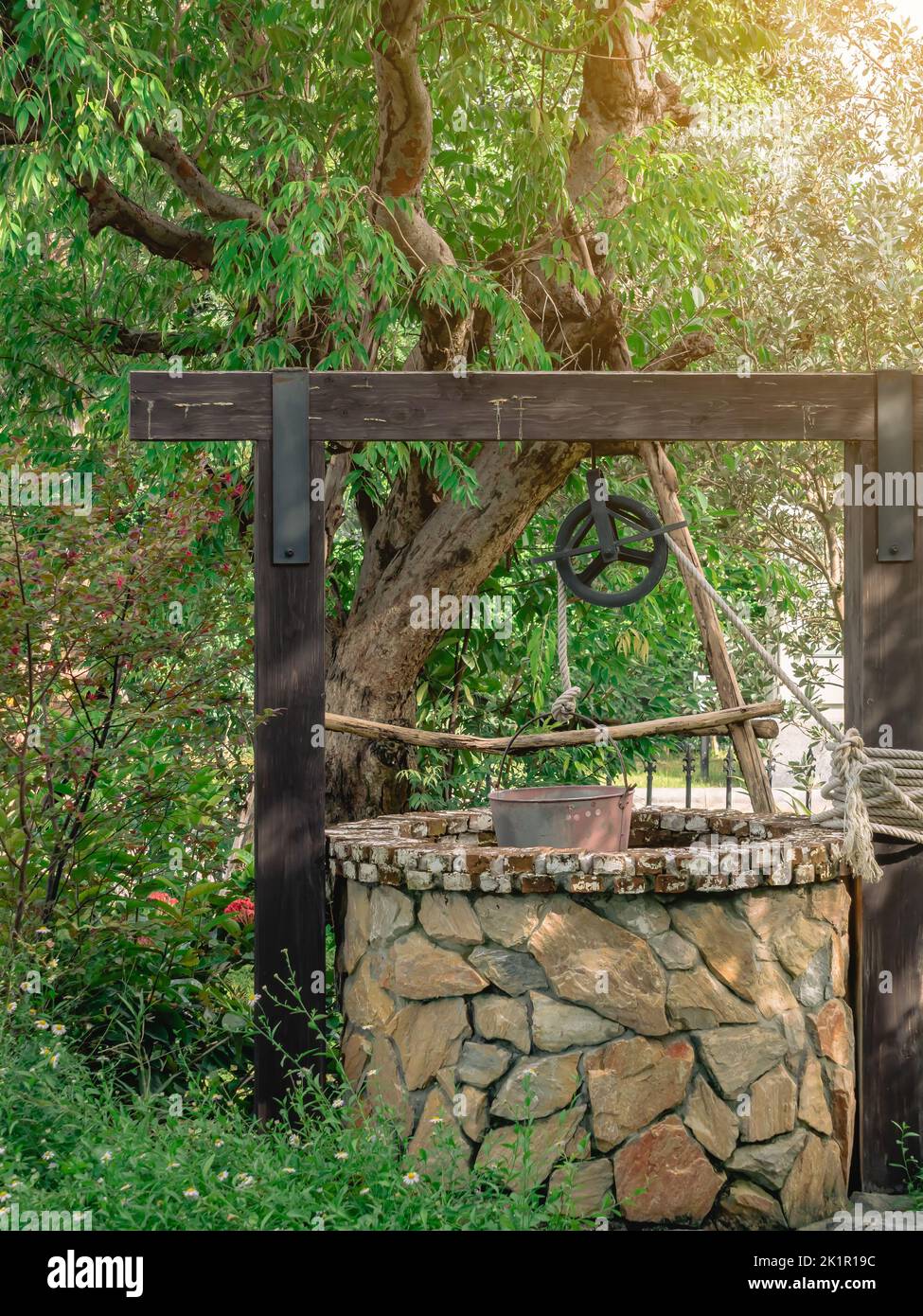 Beautiful artesian well made by stones and wheel pulley with metal ...