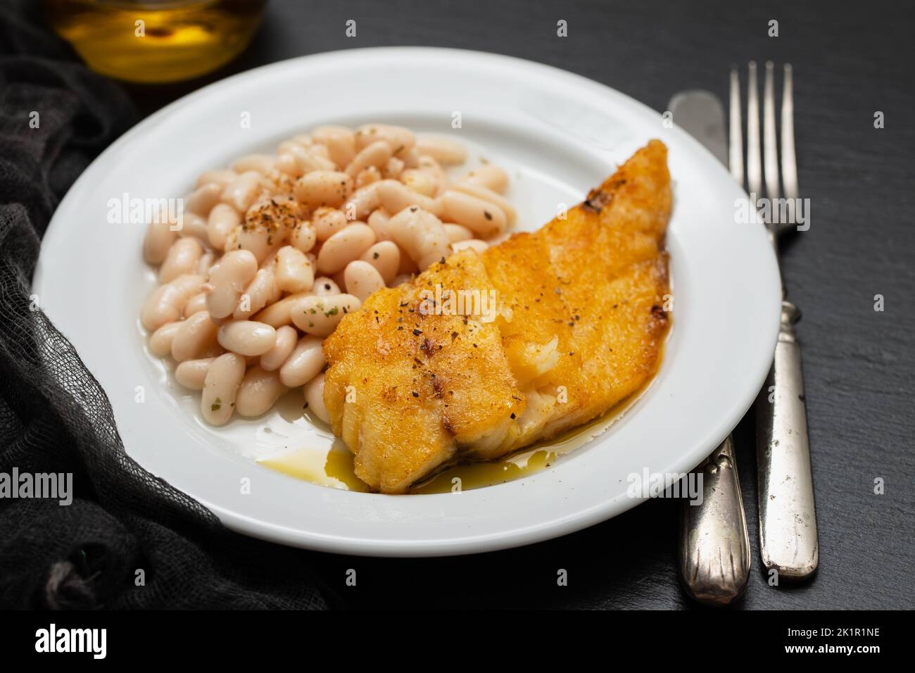 Fried cod fish with white beans on the plate Stock Photo - Alamy