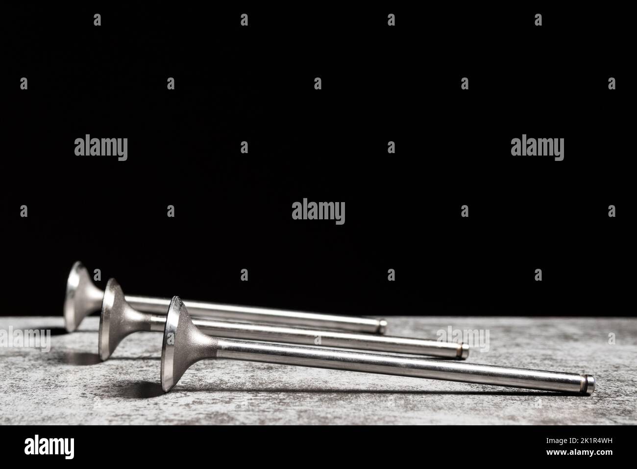 Car engine valves lie on the table on black background. Part of an ...