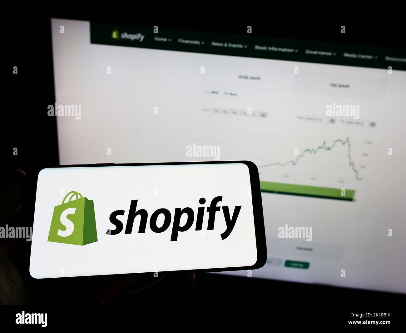 Person holding mobile phone with logo of Canadian e-commerce company ...