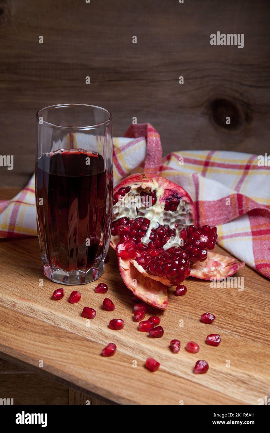 Composition of ripe red pomegranate and glass of fresh rudy juice on a ...