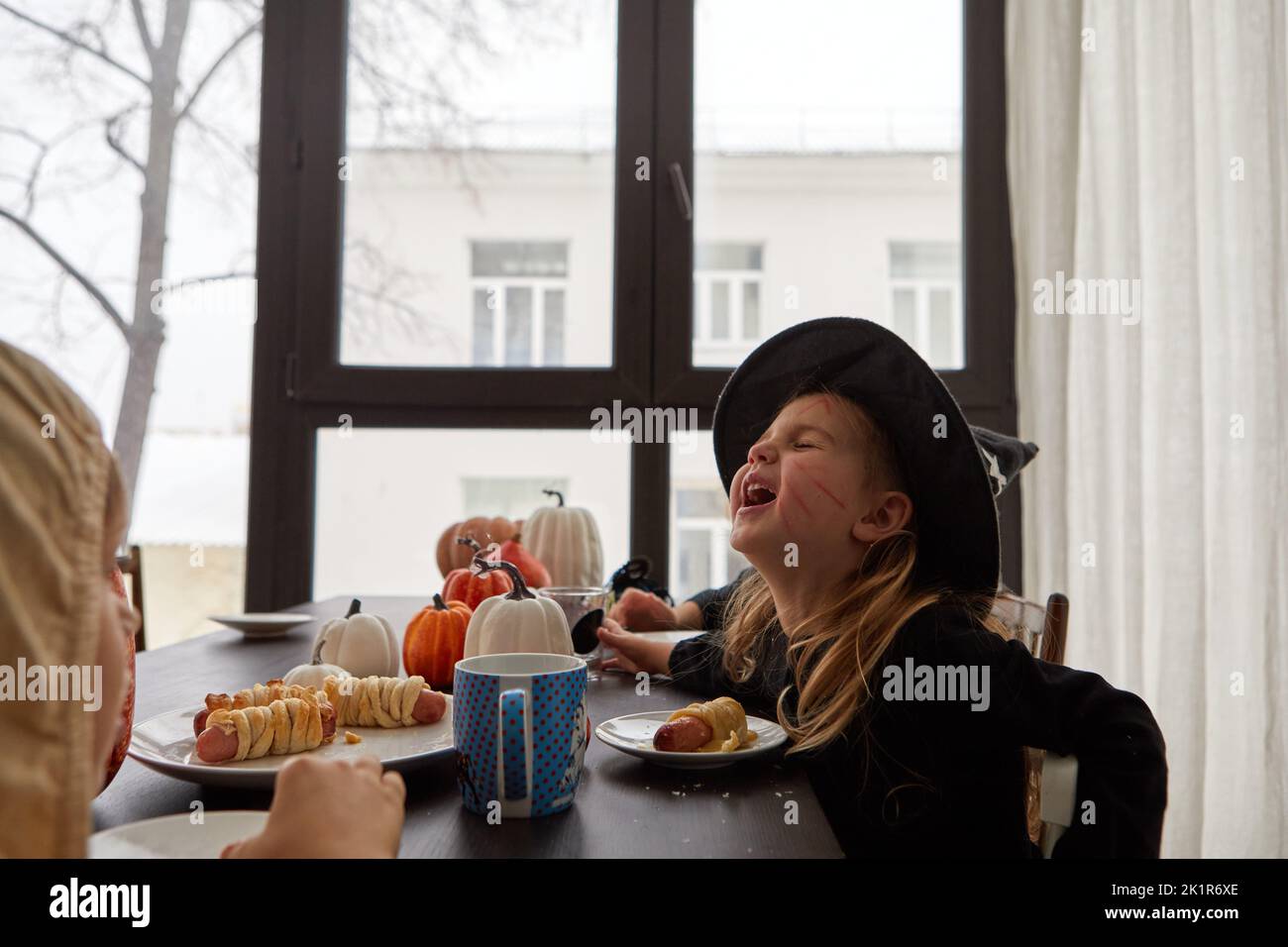 Funny girl in Halloween costume eating at table Stock Photo - Alamy