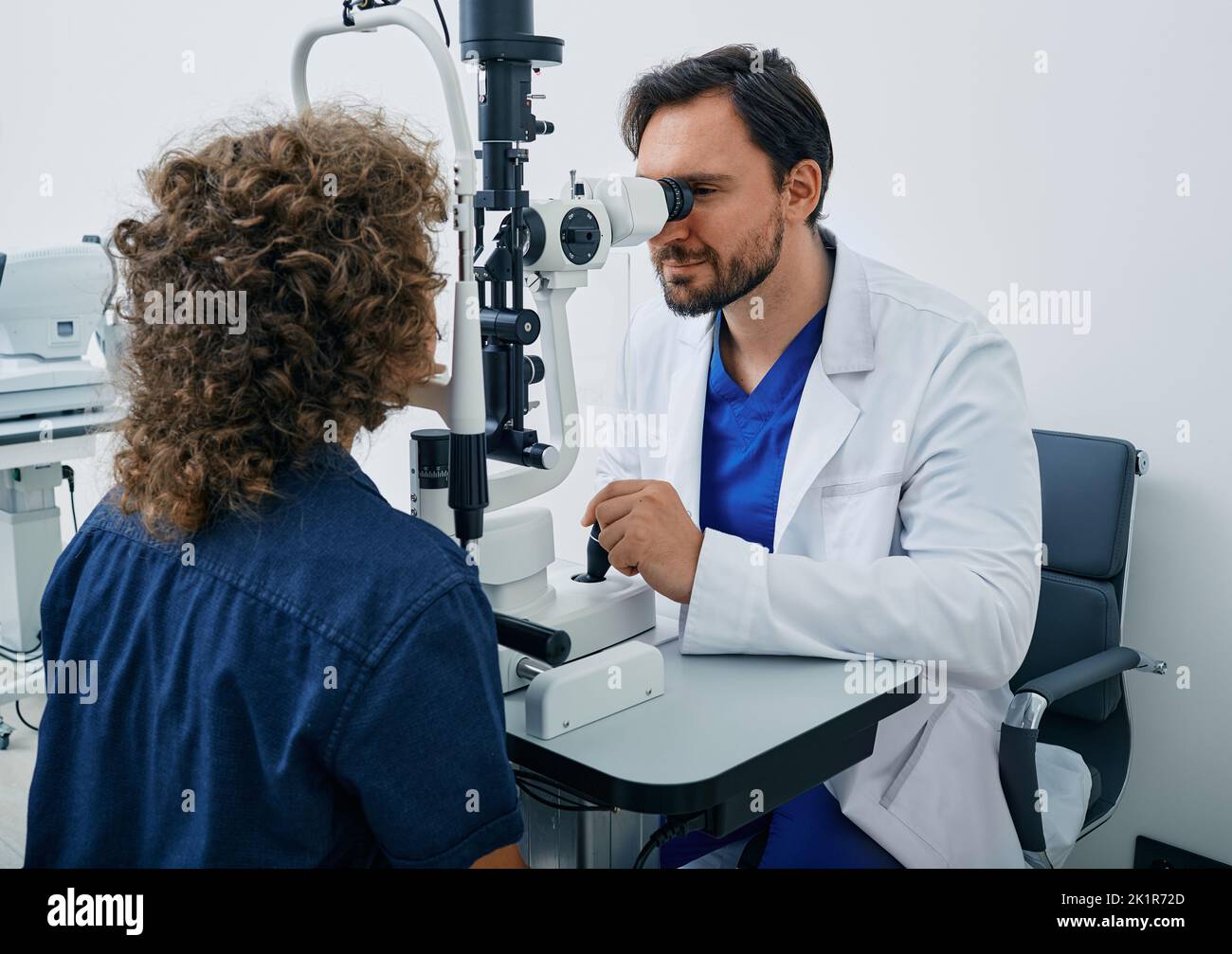 Checking eyes of child in ophthalmology clinic. Curly boy getting eye exam at ophthalmology ...
