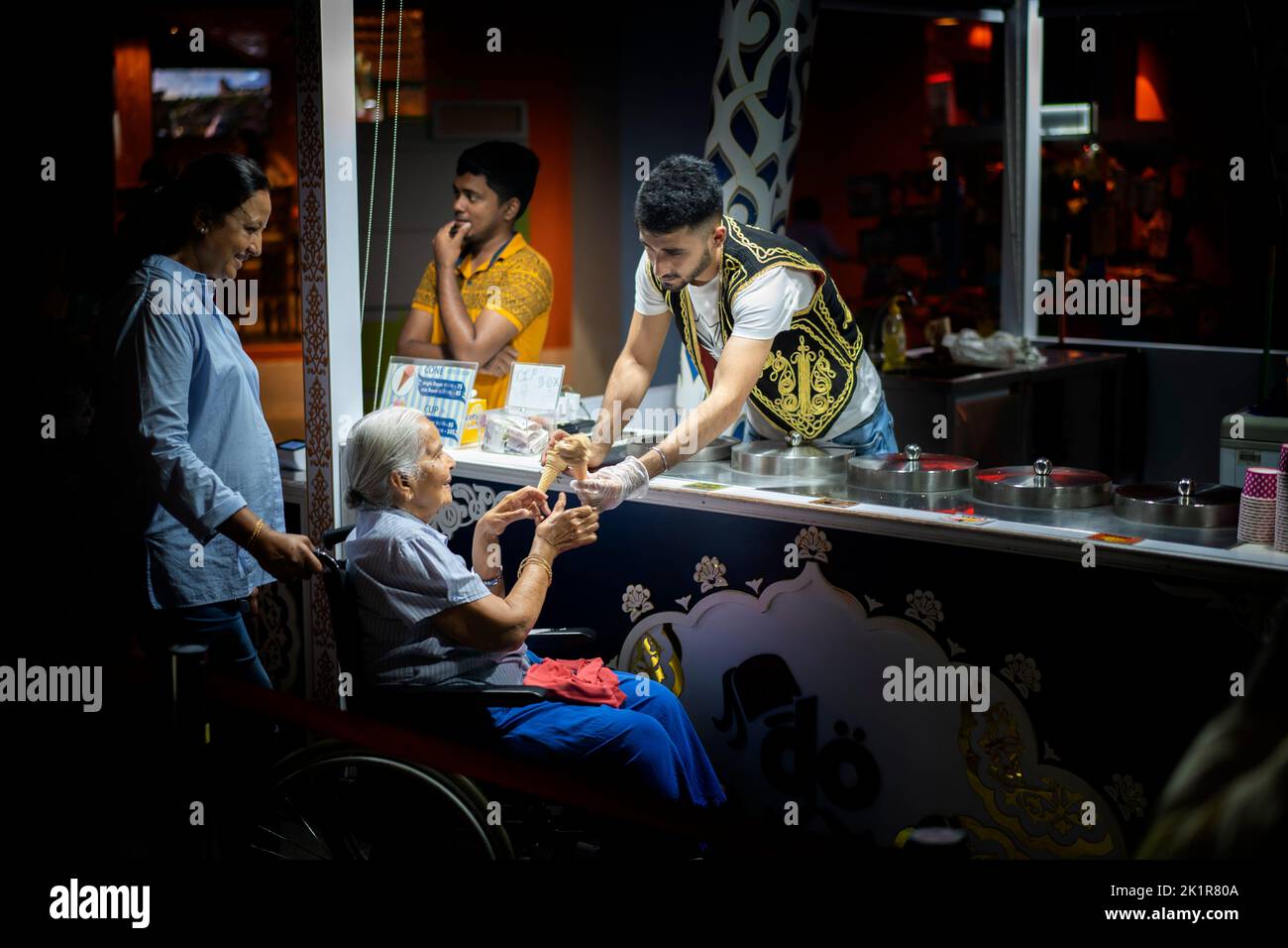 Street vendor handing an ice cream to an old lady in a wheelchair ...