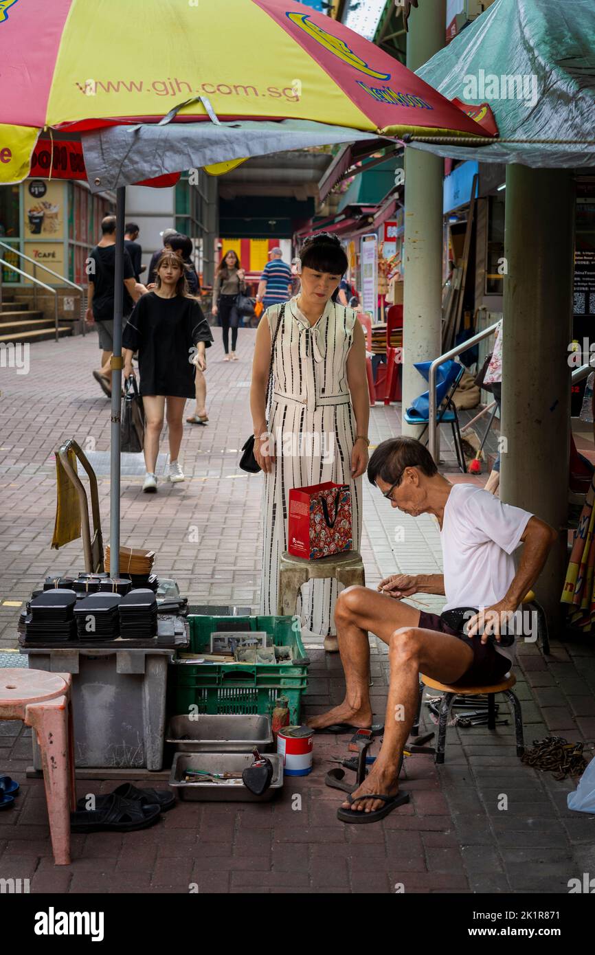 Street vendor sitting under umbrella on sidewalk in Chinatown ...