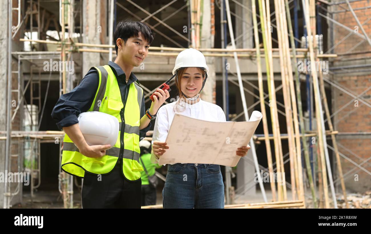 Architect team in safety helmet and reflective jacket standing front of ...