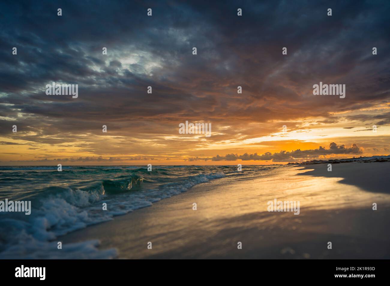A dramatic sunset over the sea waves washing the sandy beach Stock ...