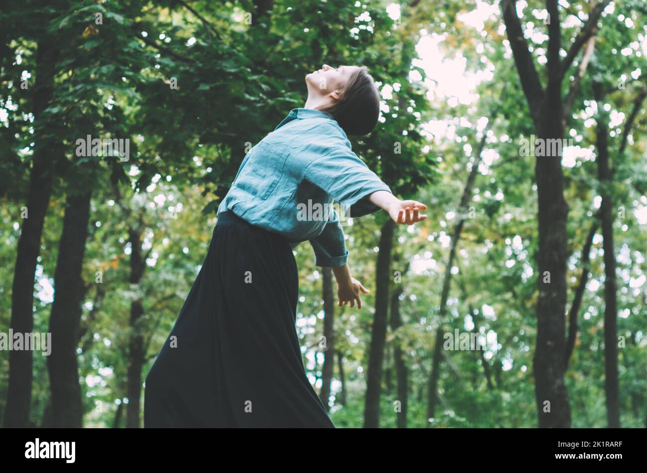 Side view of woman with arms outstretched, looking towards the sky, in ...