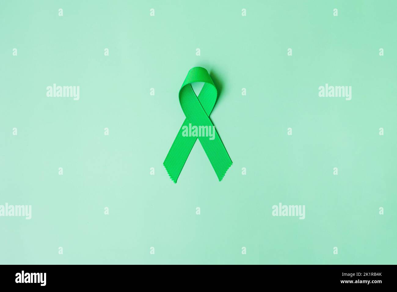 green Ribbon on green color background for supporting people living and ...