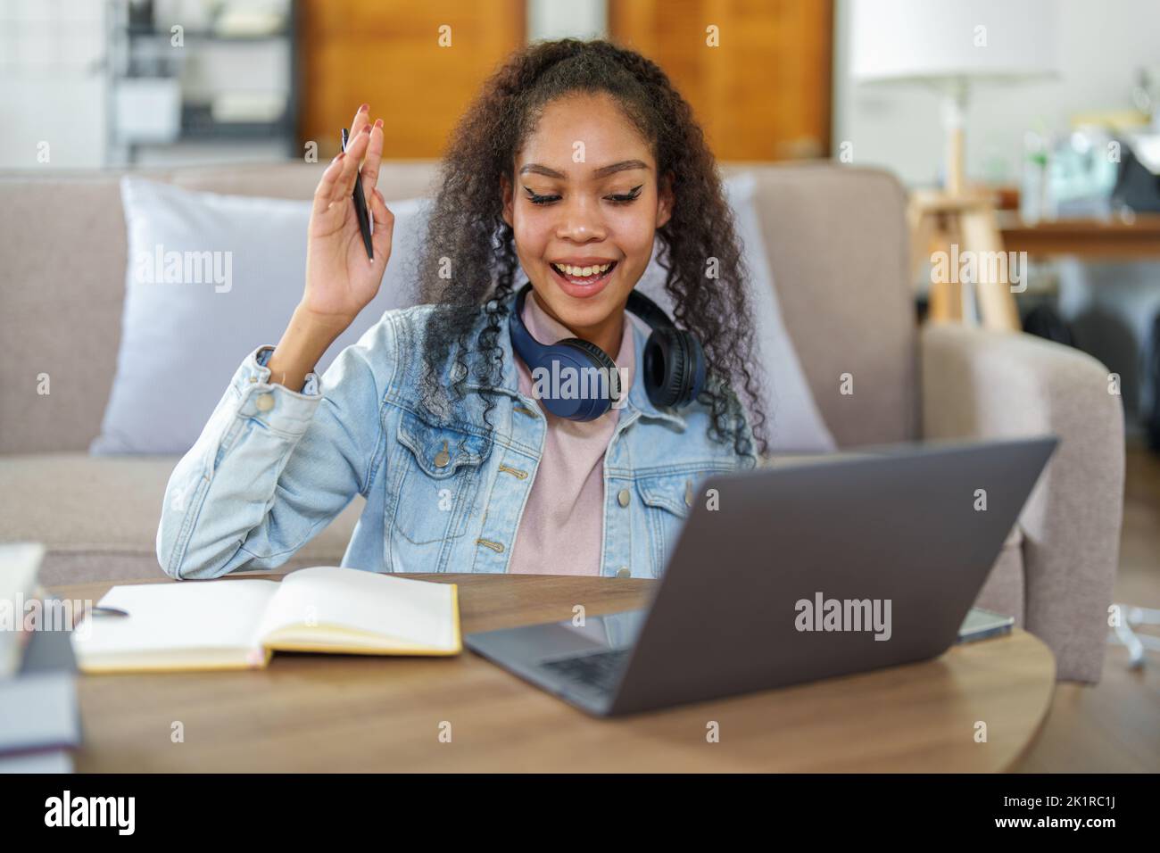 African American using a notebook and computer to study online at home ...