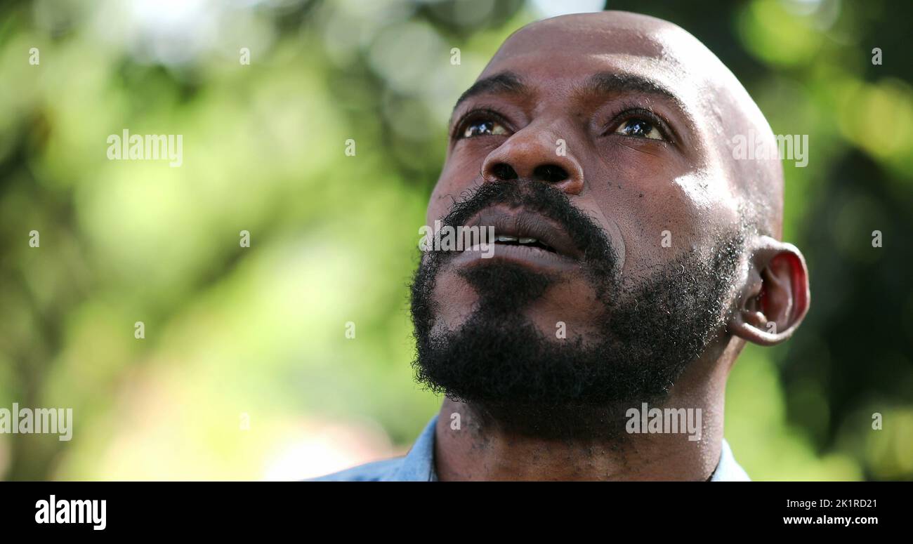 African man opening eyes to sky with HOPE and FAITH. Serious emotion ...