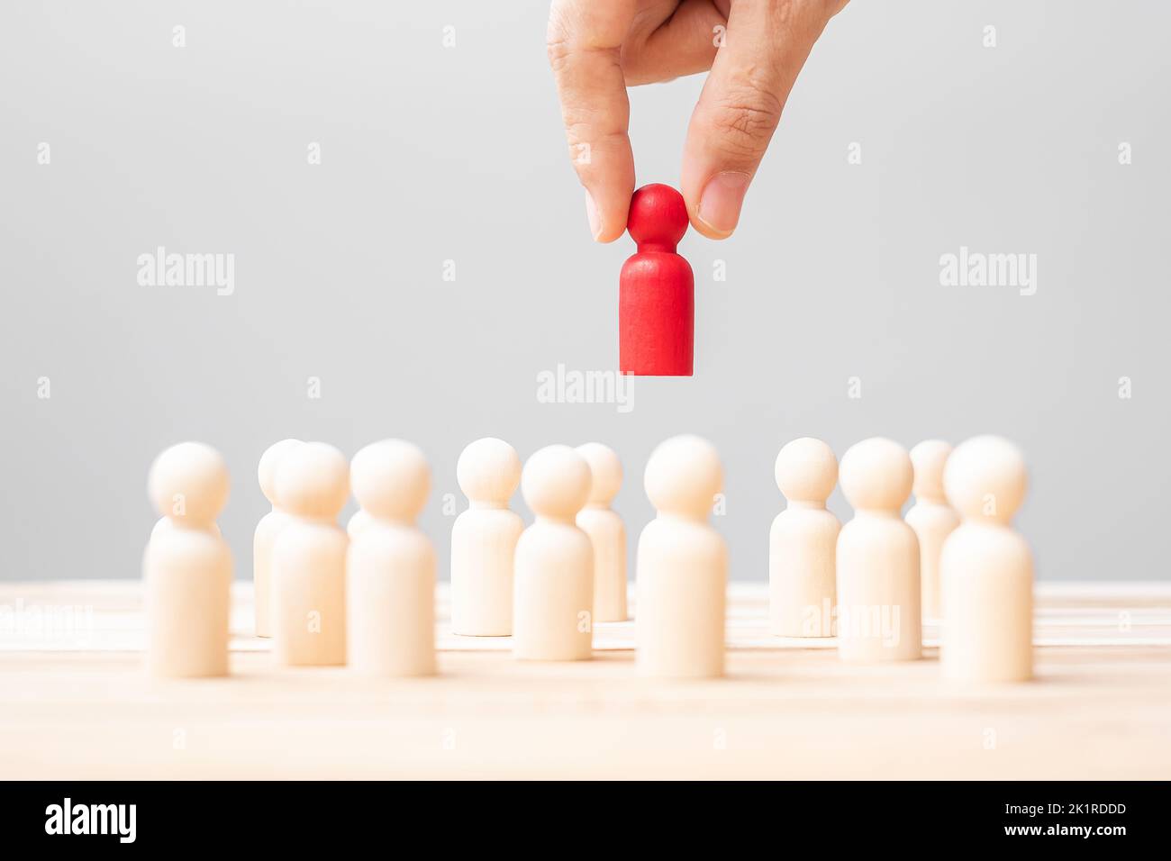 Businessman hand pulling leader man wooden from crowd of employees ...