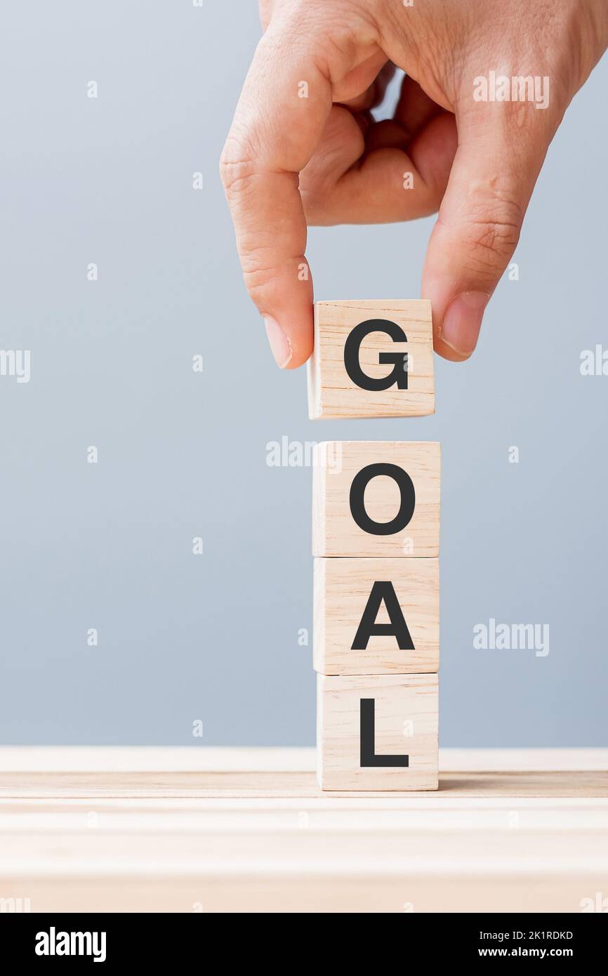 Business man hand holding wooden cube block with GOAL business word ...
