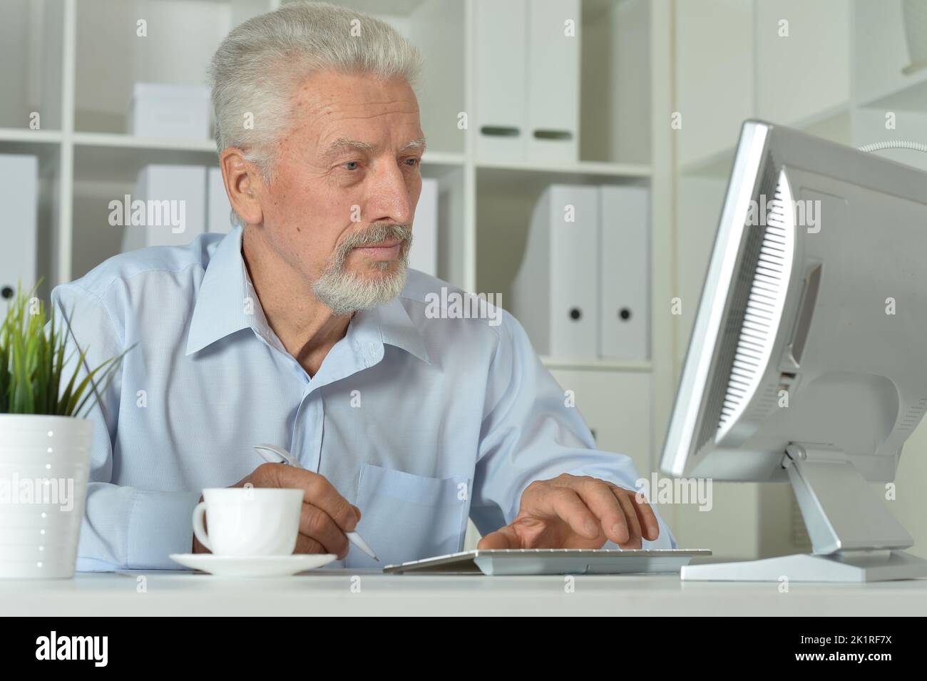 Elderly man sits with a computer in the office Stock Photo - Alamy