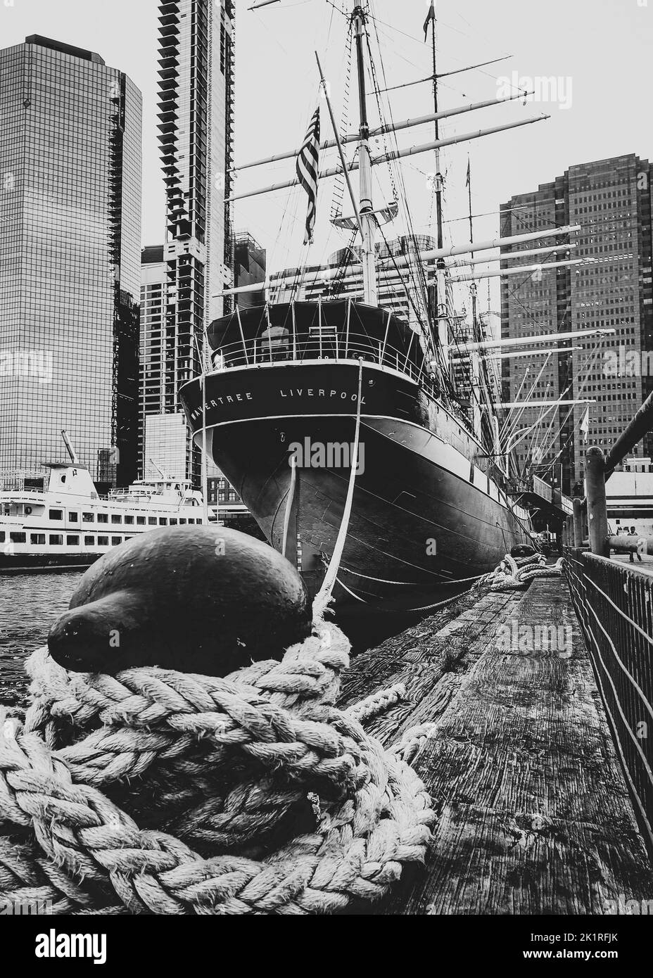 A vertical grayscale shot of a thick rope tying a huge boat by the ...