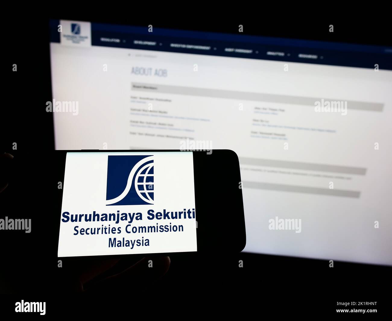 Person holding mobile phone with logo of Securities Commission Malaysia ...