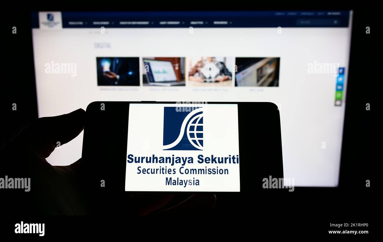 Person holding cellphone with logo of Securities Commission Malaysia ...