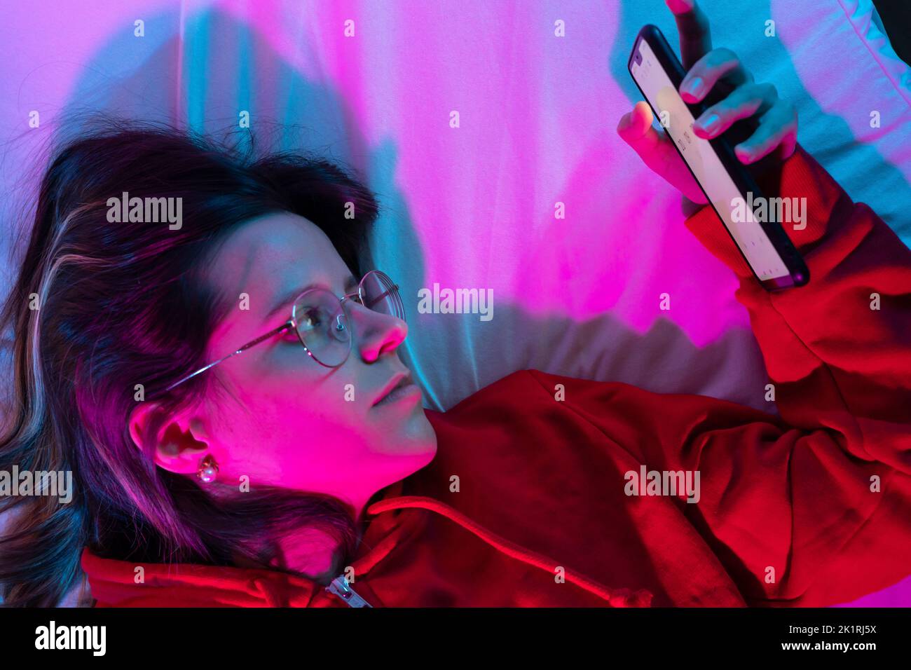 Doom scrolling on bed at night with neon lights. Technology at bed ...