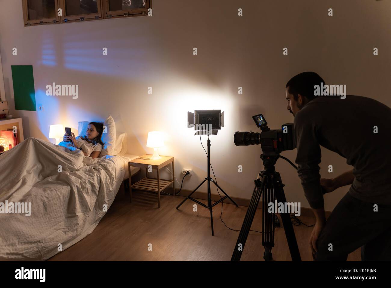 Film bedroom set with attractive model in the bed and camera operator ...