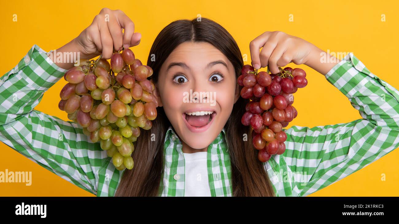 shocked teen kid with grapes bunch on yellow background Stock Photo - Alamy