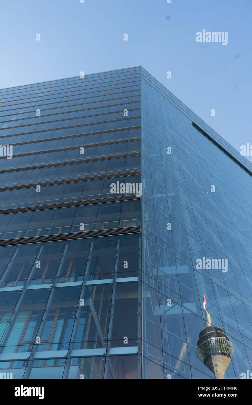 A vertical shot of a modern glassy building with Rhine Tower reflection ...
