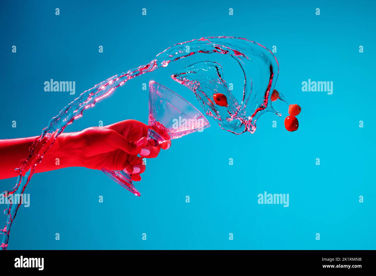 Female hand spilling over Martini cocktail with cherries splashing over ...