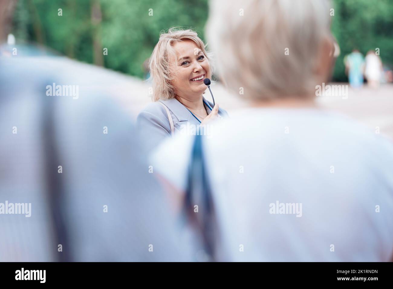 female tour guide with a microphone standing among a group of tourists ...