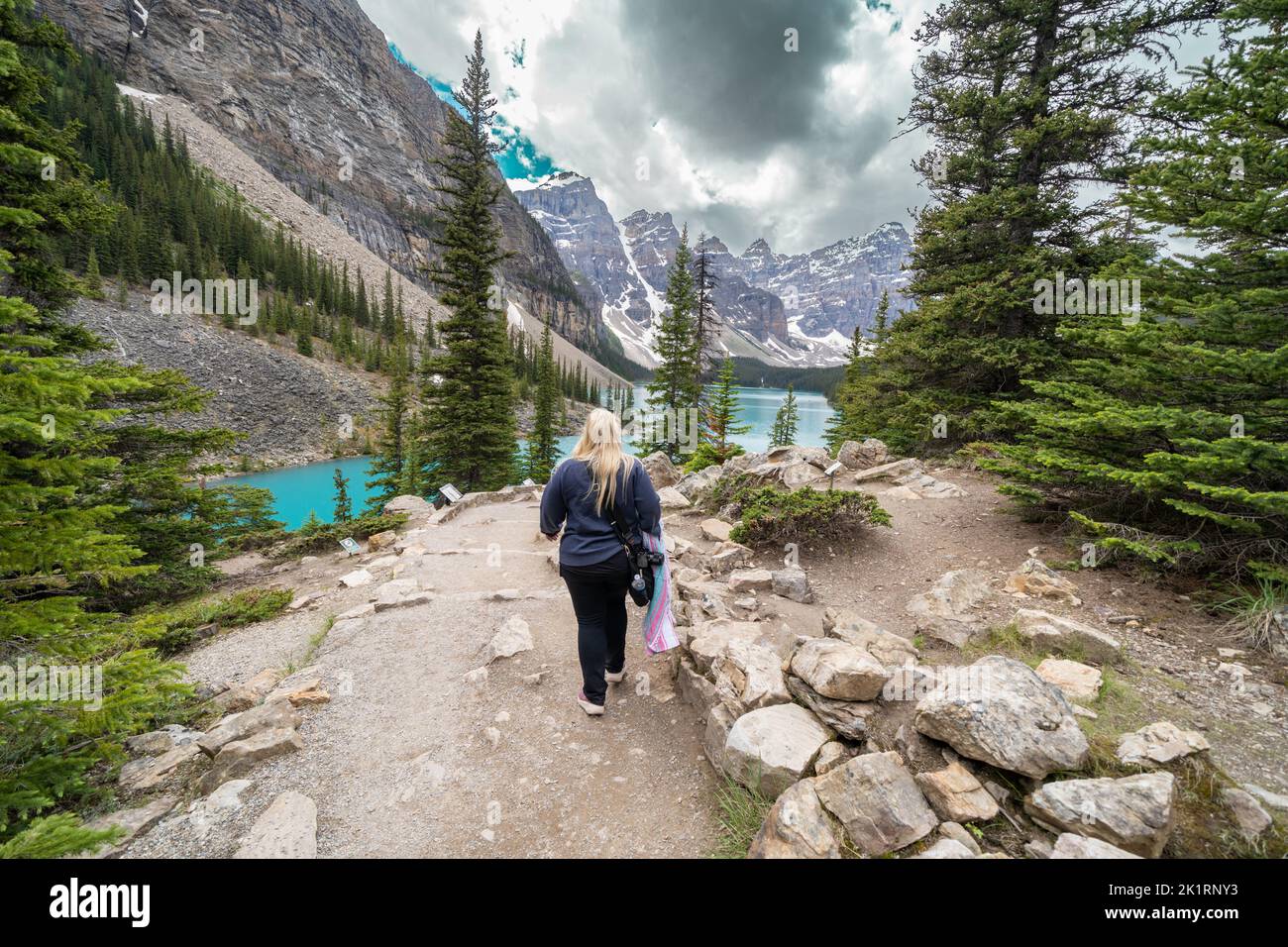Woman carrying camera gear walks the Rockpile Trail at Moraine Lake in ...
