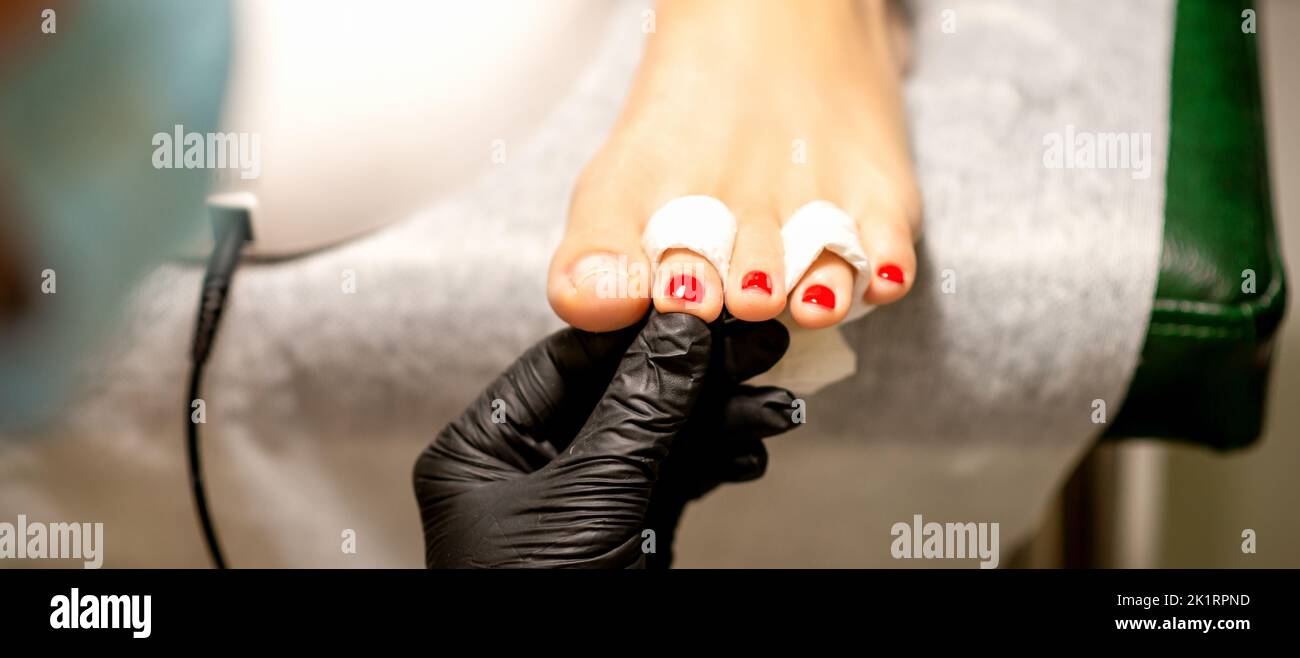 Nail painting process. A manicure master hand holds red painted ...