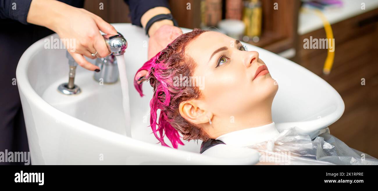 Washing dyed female hair. A young caucasian woman having her hair ...