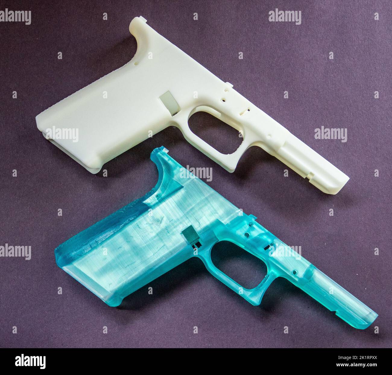 A closeup of 3D printed turquoise and white "Ghost Gun" on a dark ...