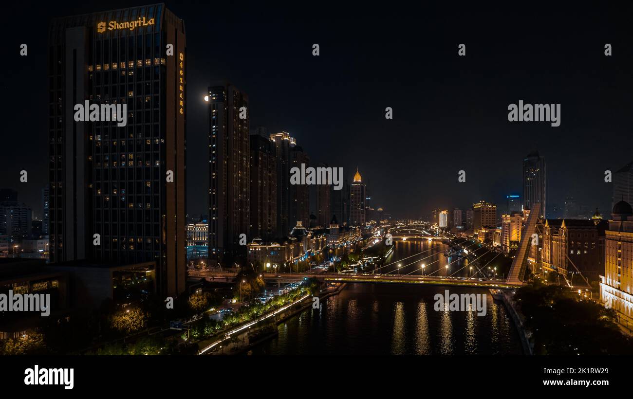An aerial night view of of the city over Haihe River in Tianjin, China ...