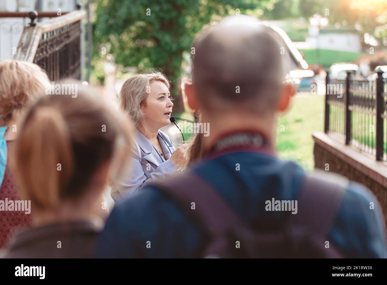 female guide is telling a group of tourists about something Stock Photo ...