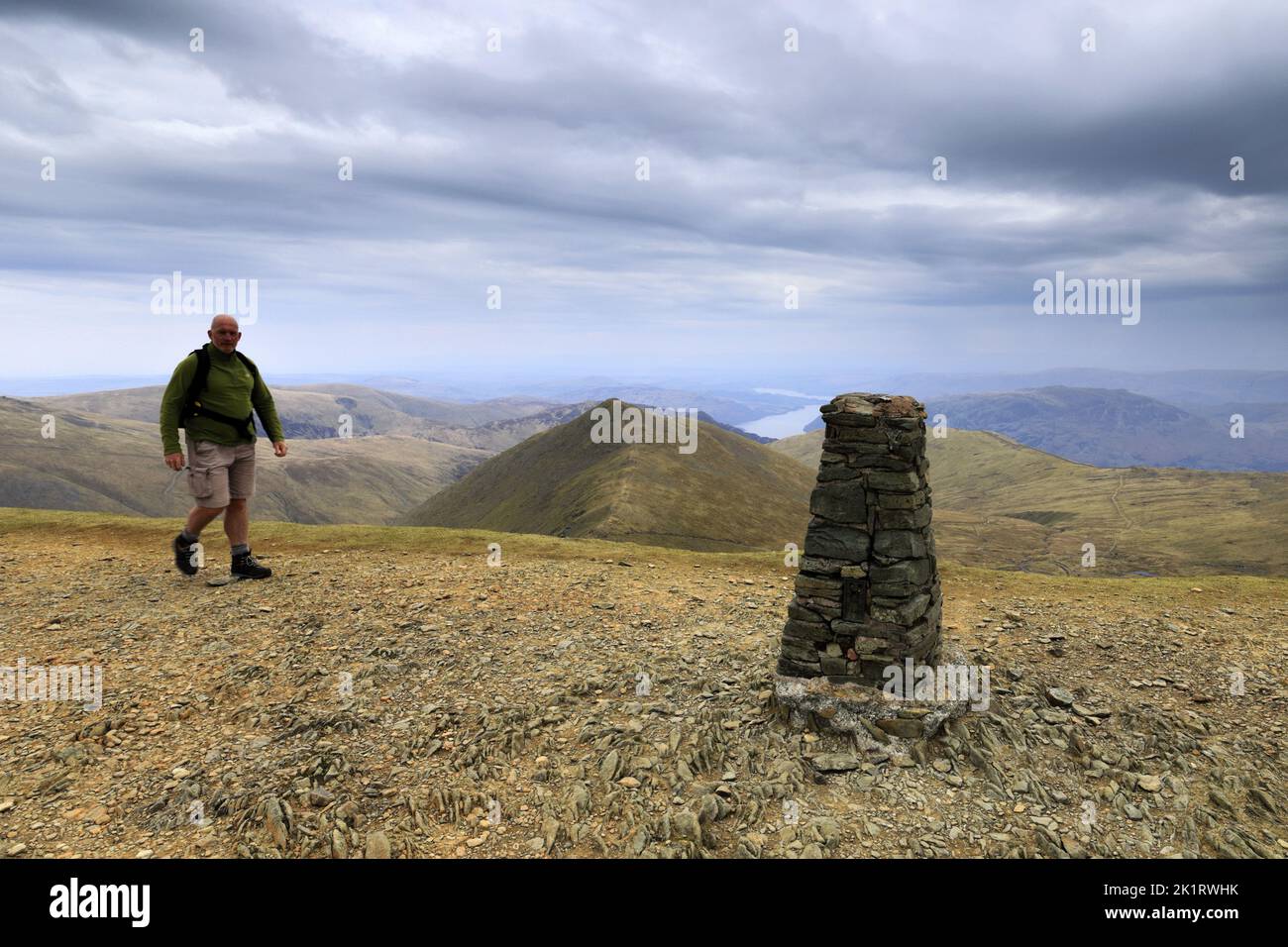 Walker at the summit cairn of Helvellyn fell, Lake District National ...