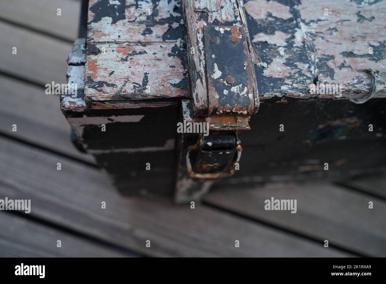 A closeup of an old wooden box with a chipped surface and rusty metal ...