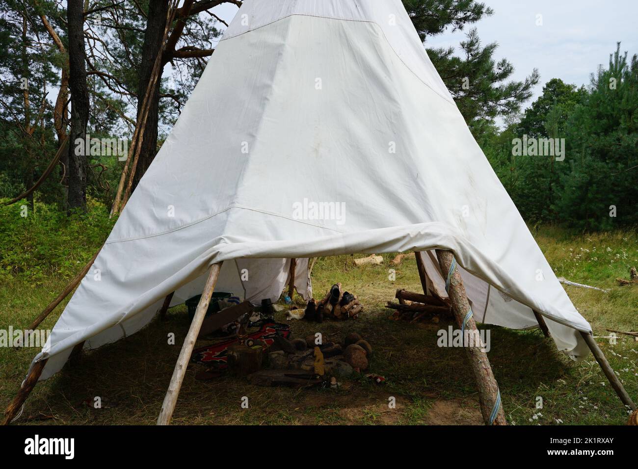 A triangular tent made by long branches covered by white cloth in a ...