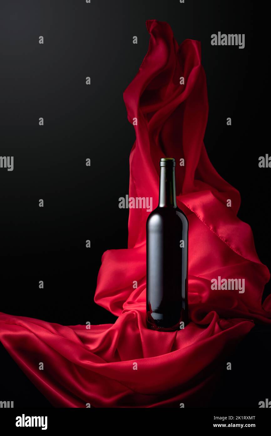 Bottle of red wine on a black background with flutters red cloth Stock ...