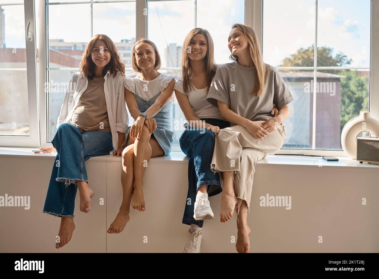Girls having fun on window sill. Four caucasian girls sitting on window ...