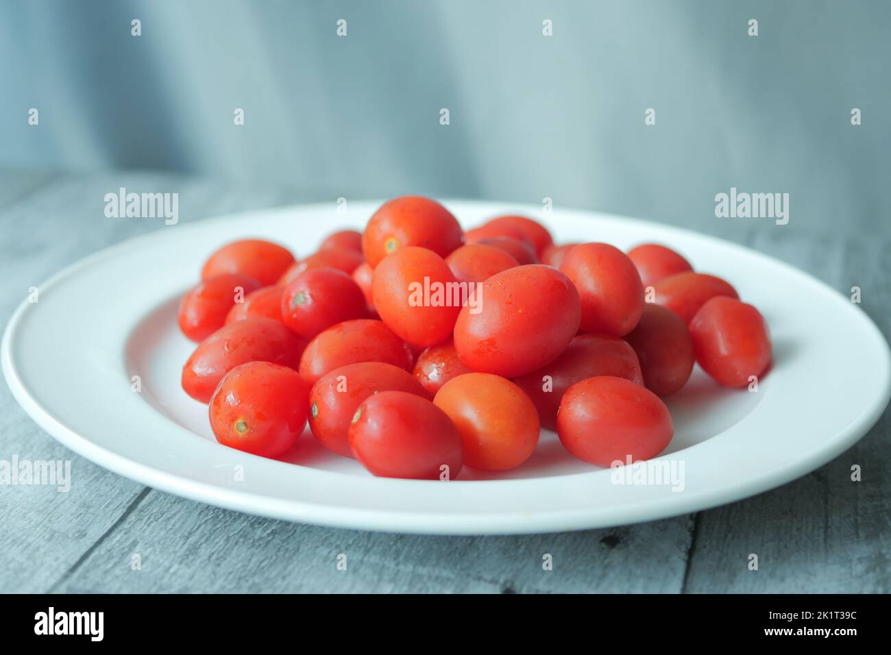 red color small tomato on a plate on table Stock Photo - Alamy