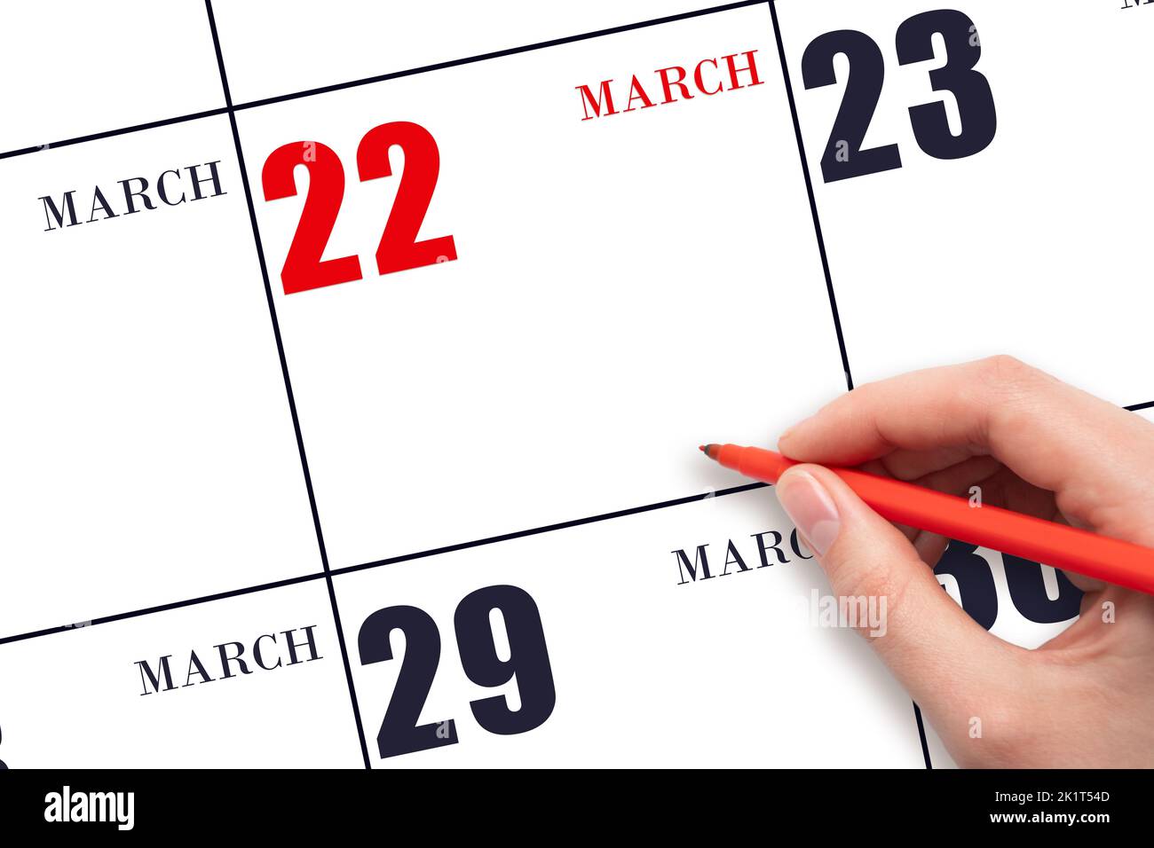 22nd day of March. A hand holding a red pen and pointing on the ...