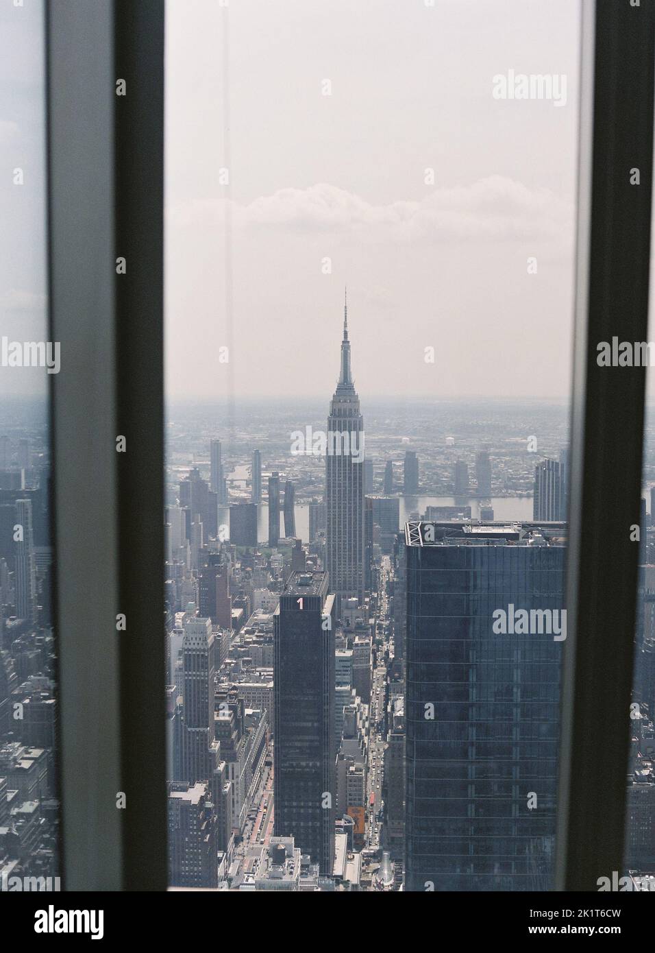 A vertical shot of the Empire State Building seen through a window, New ...