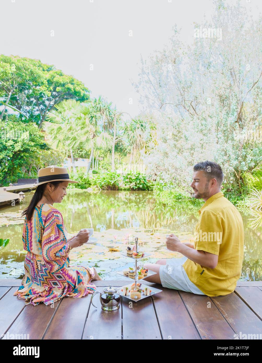 Afternoon tea at a water pond, high tea in a tropical garden in ...