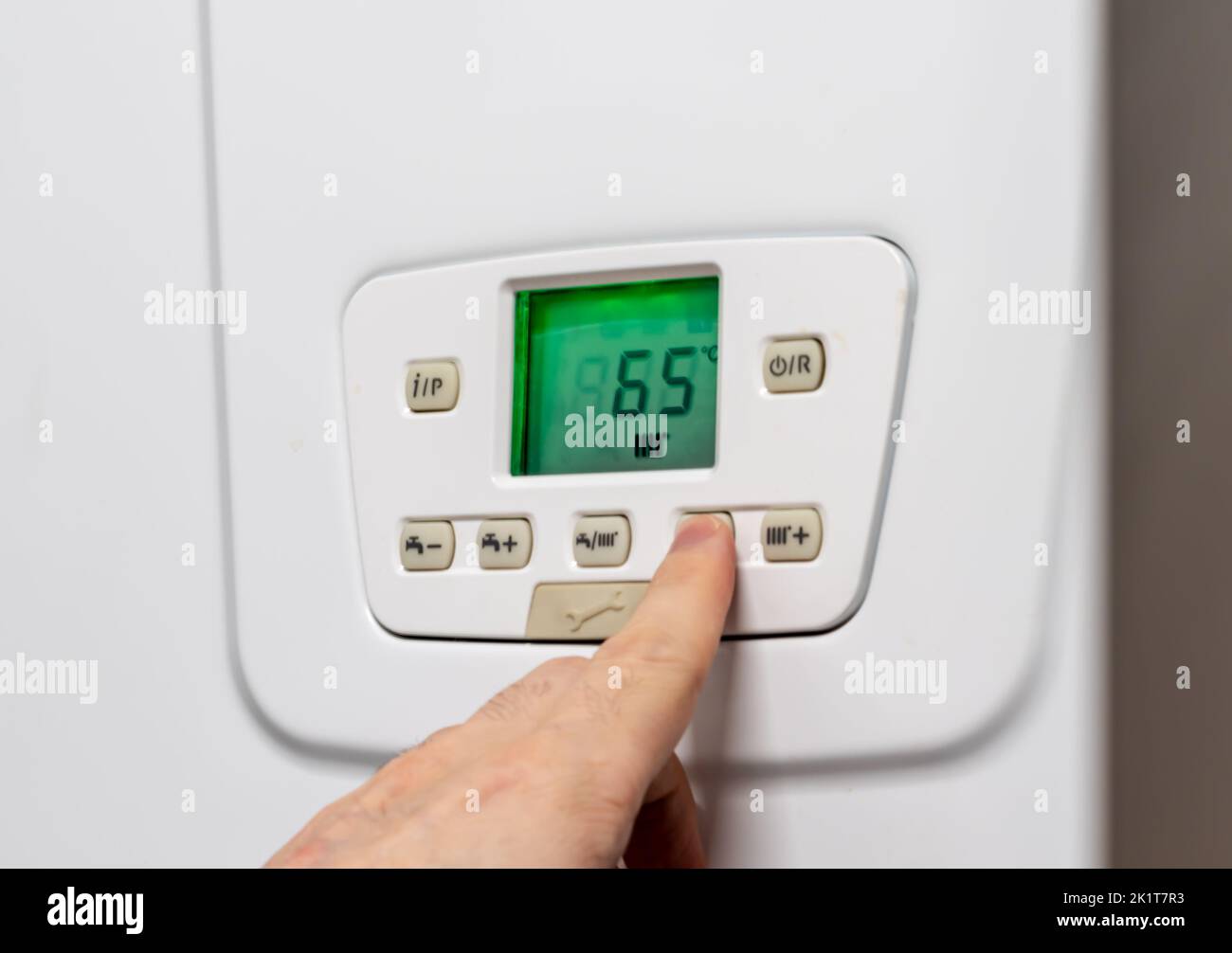 A person regulating the heating temperature by pressing buttons on the ...