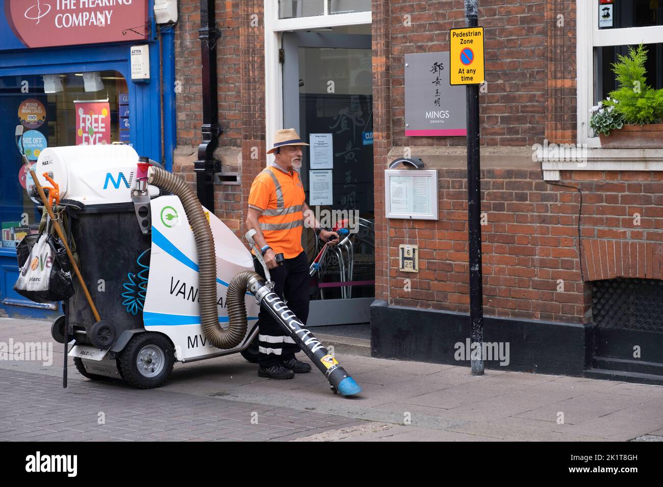 Municipal employee cleans the sidewalk with an electric municipal waste ...