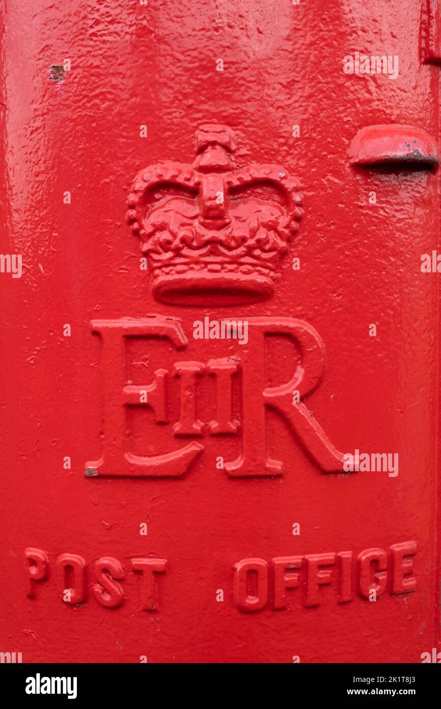 Close-up of a traditional round red British mail box with a crown and ...