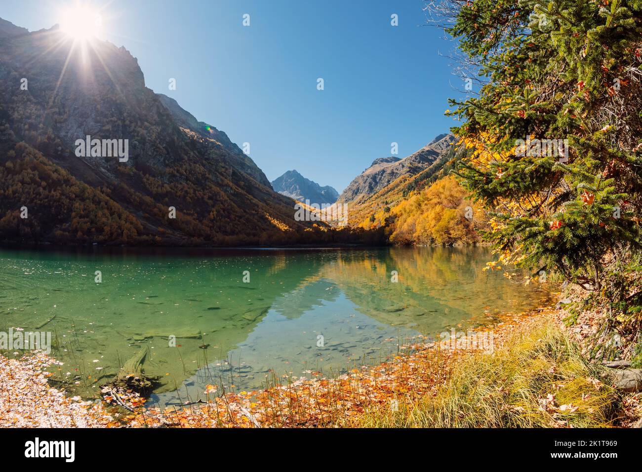 Mountain lake with transparent water, sun light and colorful autumnal ...